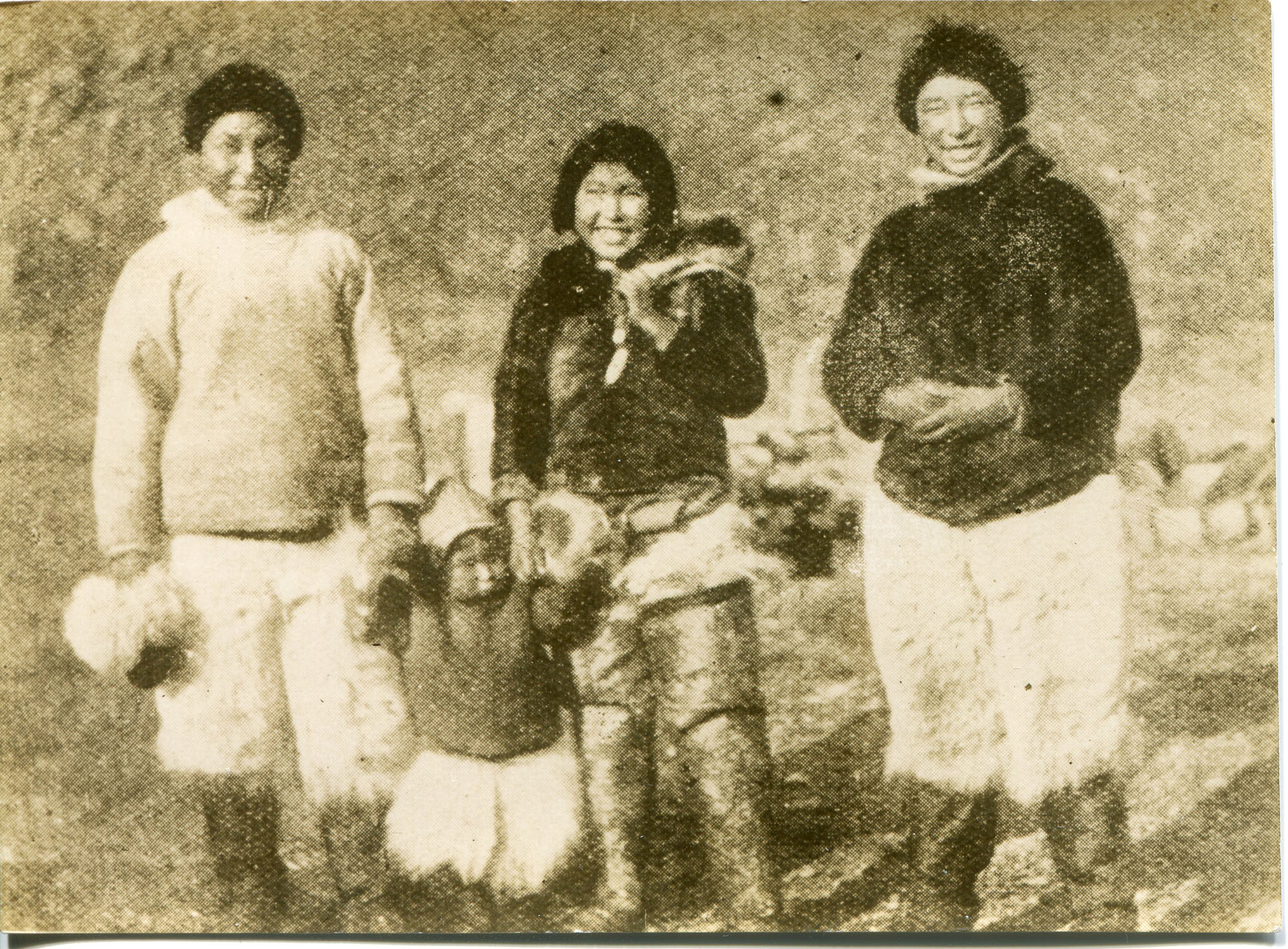 Photographic image of four Eskimos. Three are adults and one is an ...